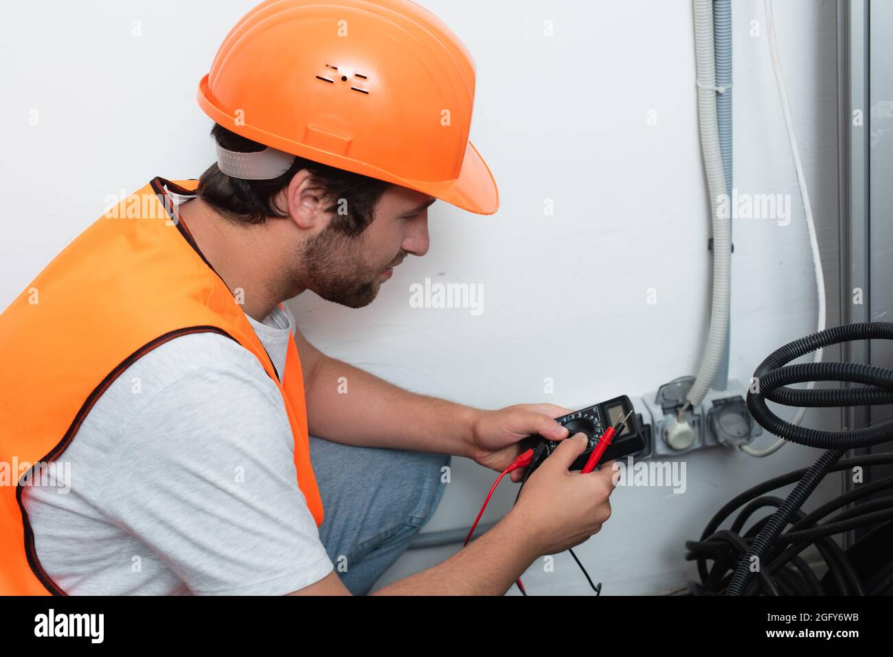 Side view of workman holding electrical tester near sockets Stock Photo ...