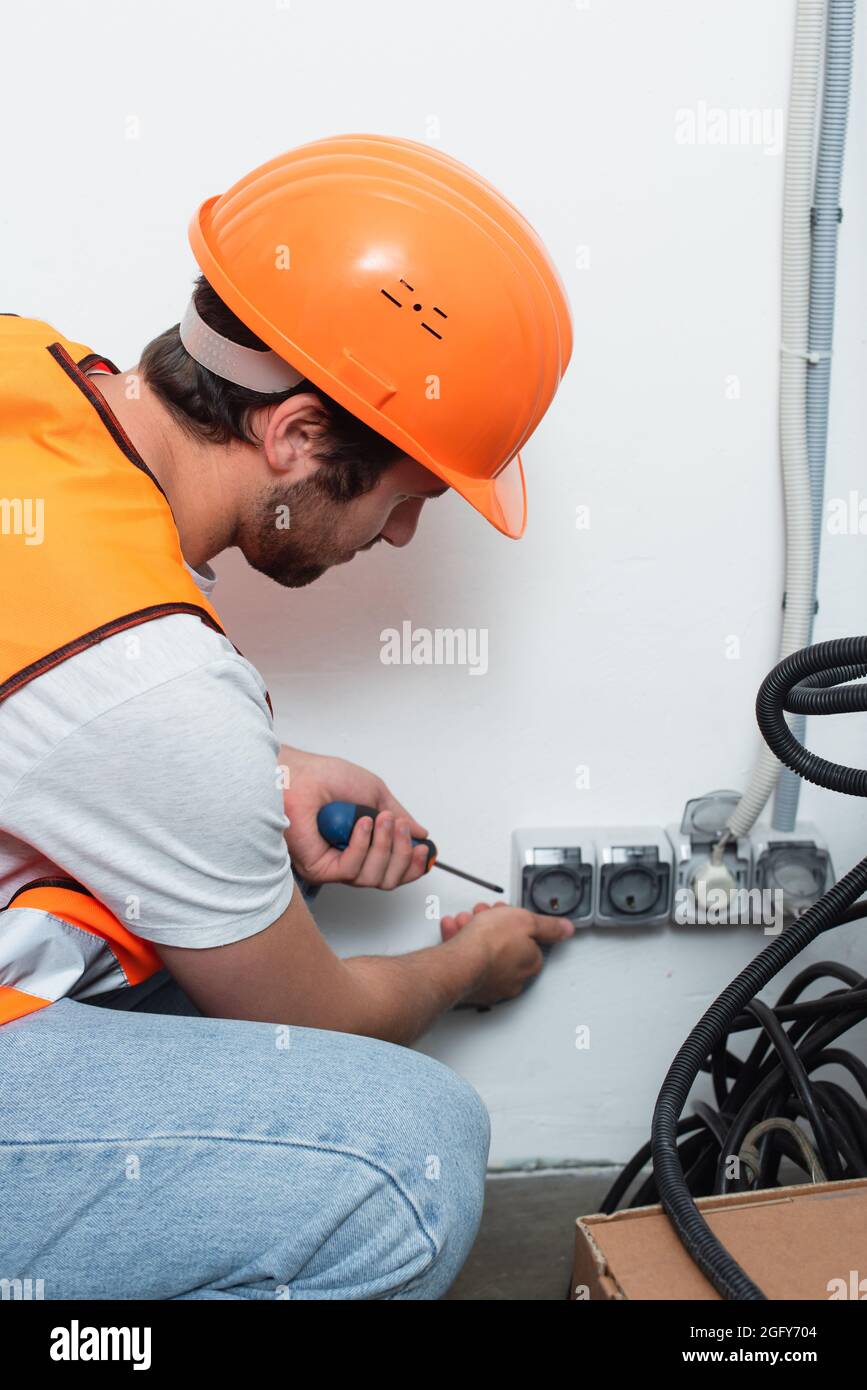 Side view of workman holding screwdriver near sockets Stock Photo - Alamy