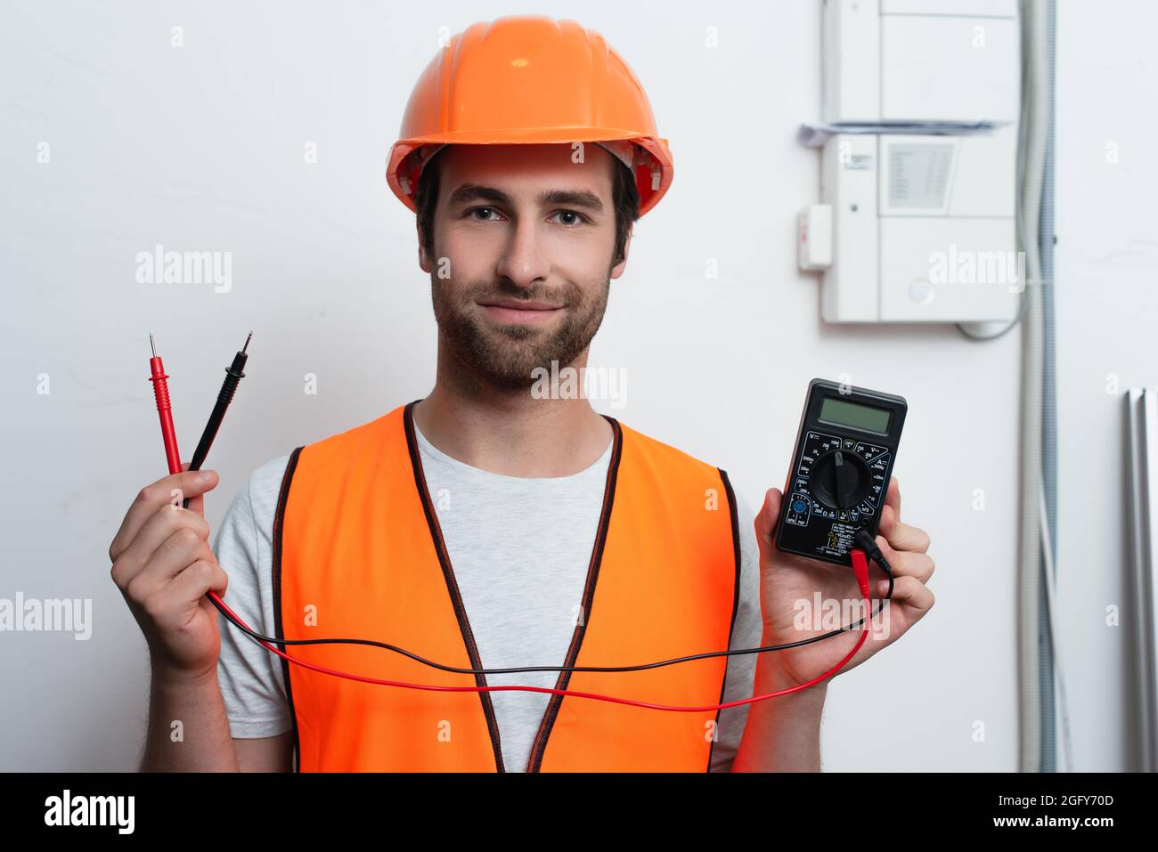 Workman in hard hat holding electrical tester Stock Photo - Alamy