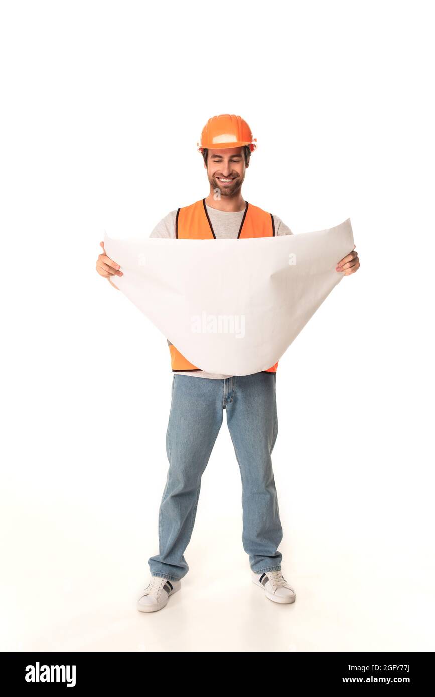 Full length of smiling builder looking at blueprint on white background ...