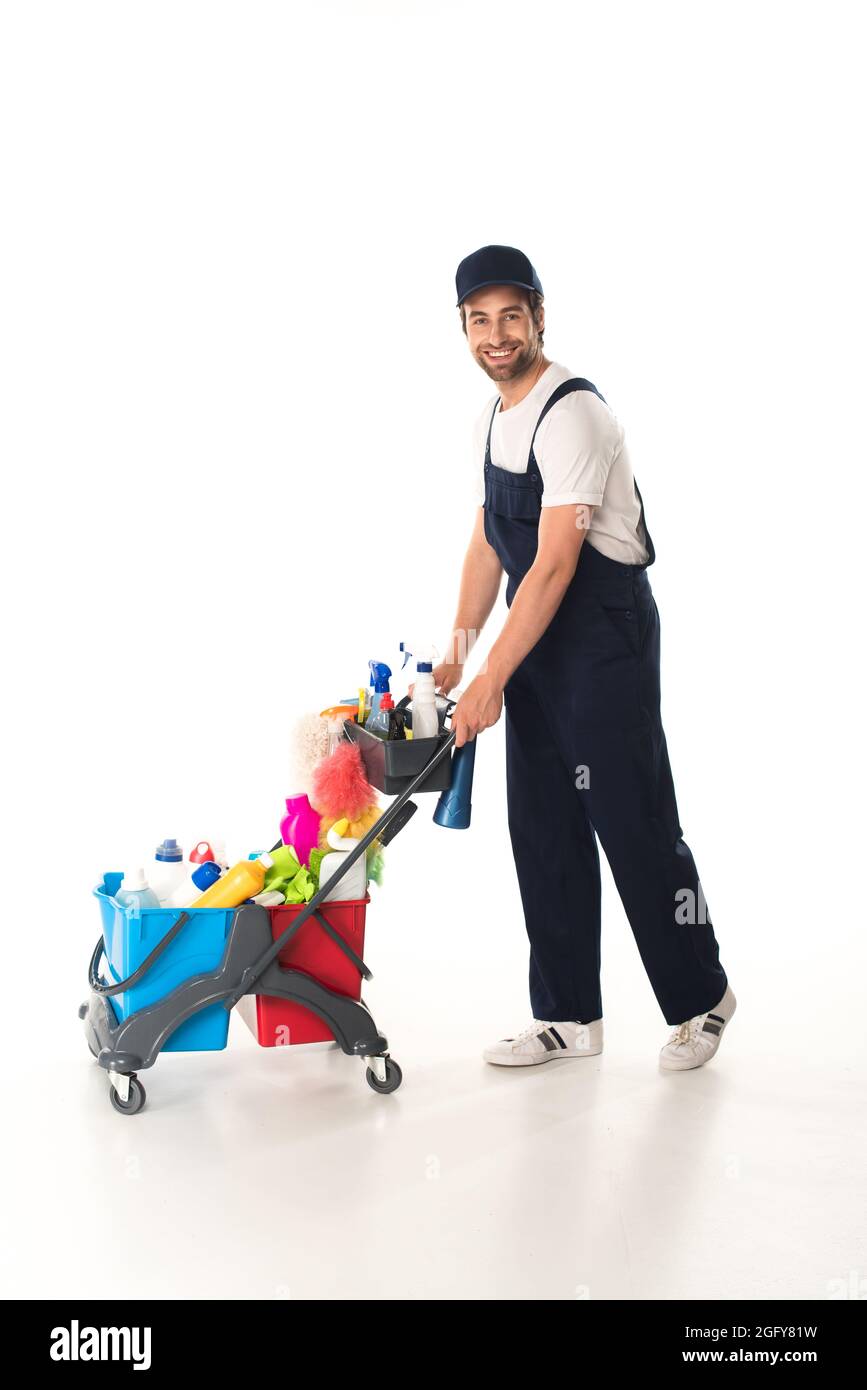 Smiling worker of cleaning company standing near cart with detergents ...