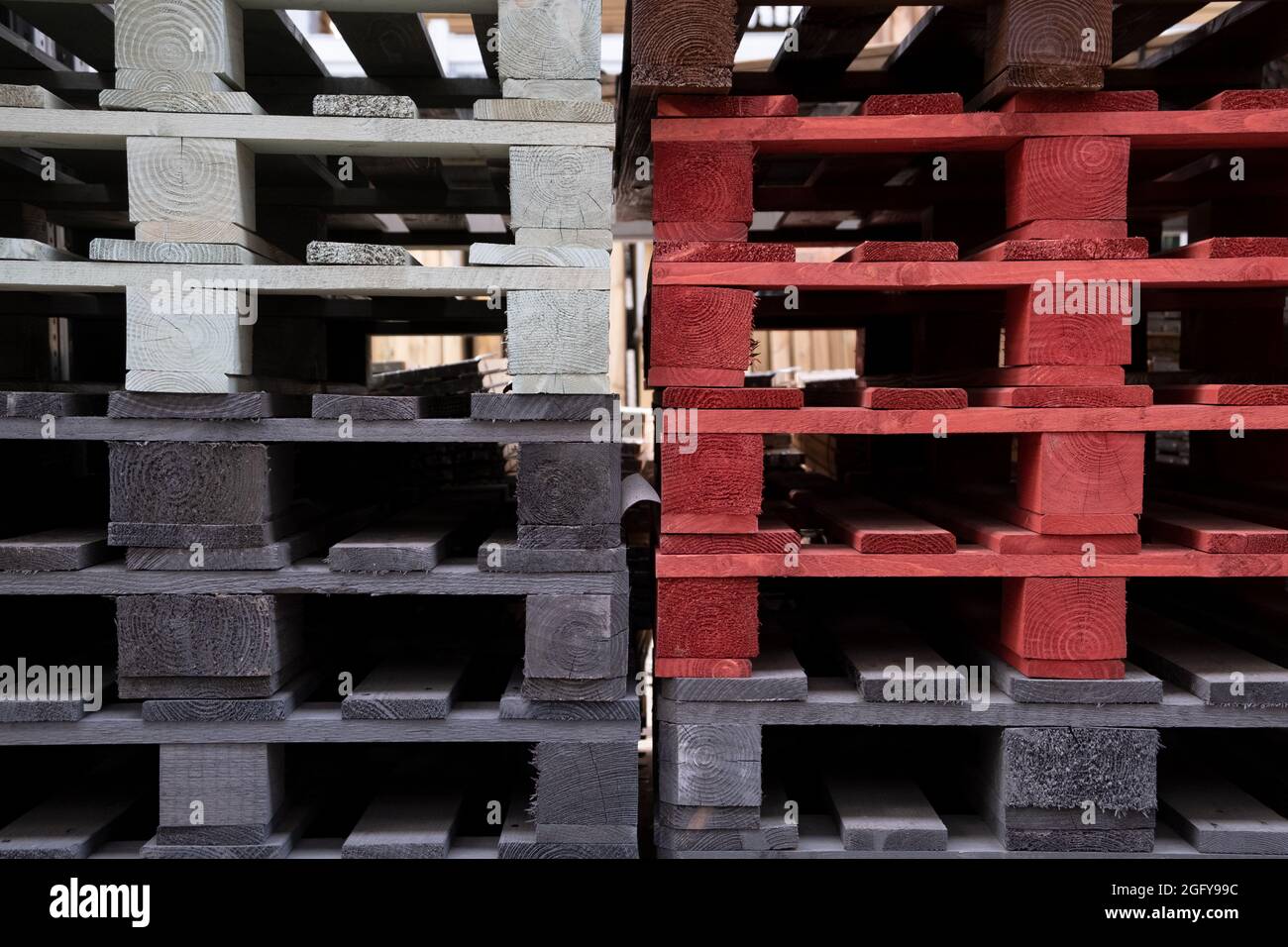 Different colors of wooden pallets are stacked in a row at hardware ...