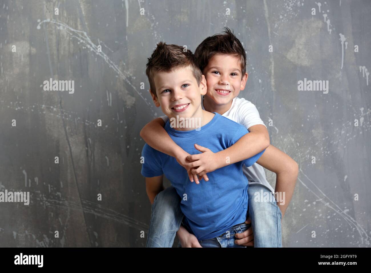 Cute little brothers standing on grey textured background Stock Photo ...