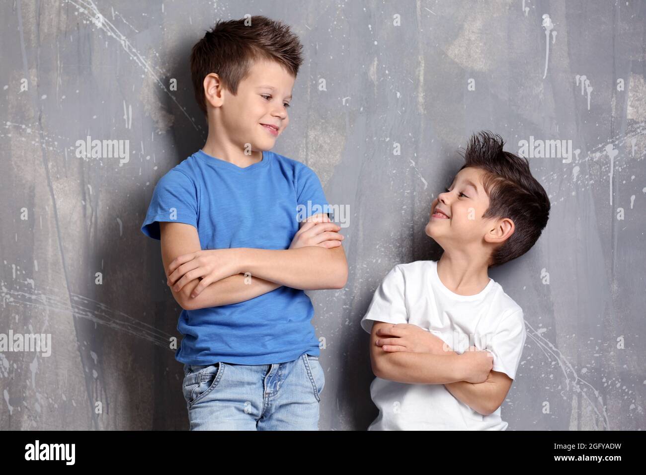 Cute little brothers standing on grey textured background Stock Photo ...