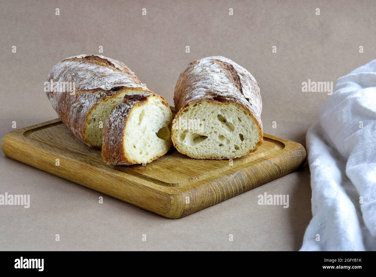 Bread loaf, cut into pieces, on wooden cutting board. Baked bread and ...