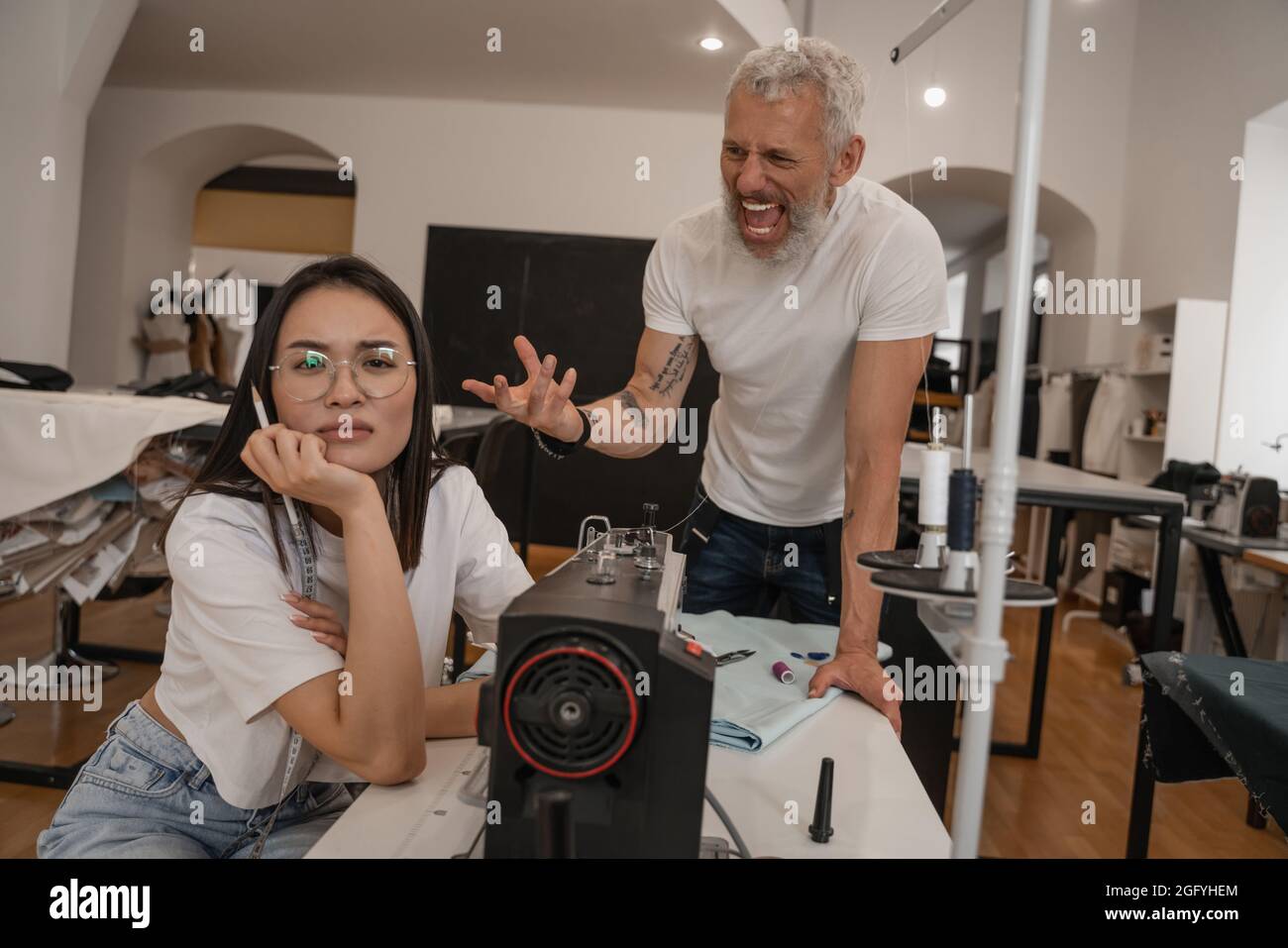 Angry designer screaming near asian colleague in atelier Stock Photo ...