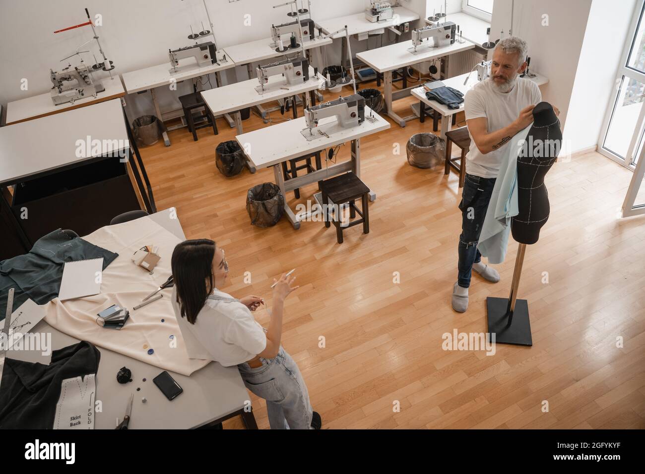 Overhead view of interracial designers talking near mannequin in studio ...