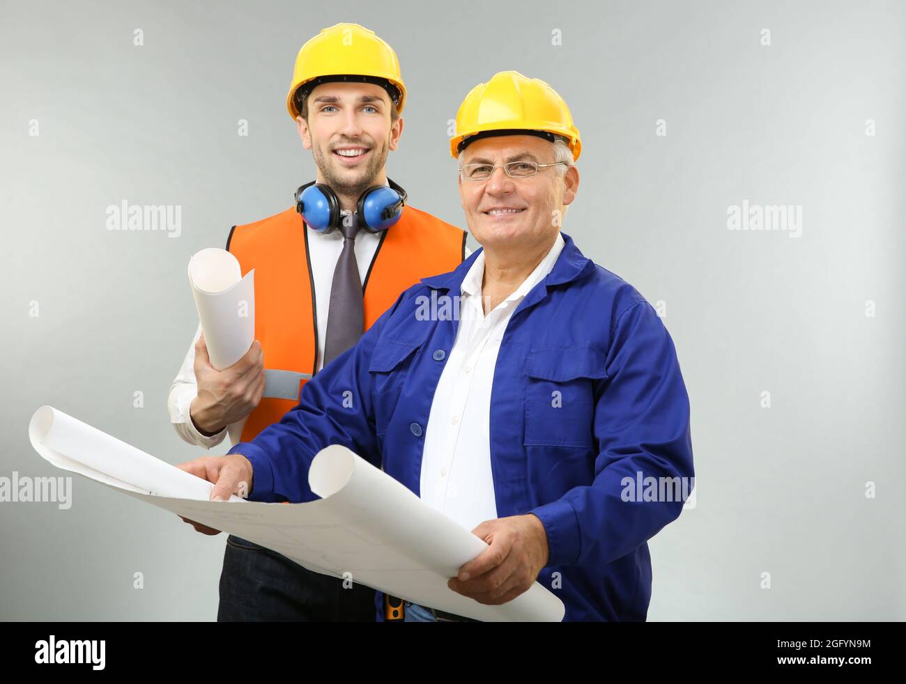 Handsome engineer and worker with drawings of new project, on light ...