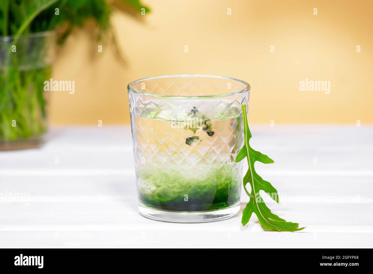 Green Chlorophyll drink in glass with water on white table, Orange ...