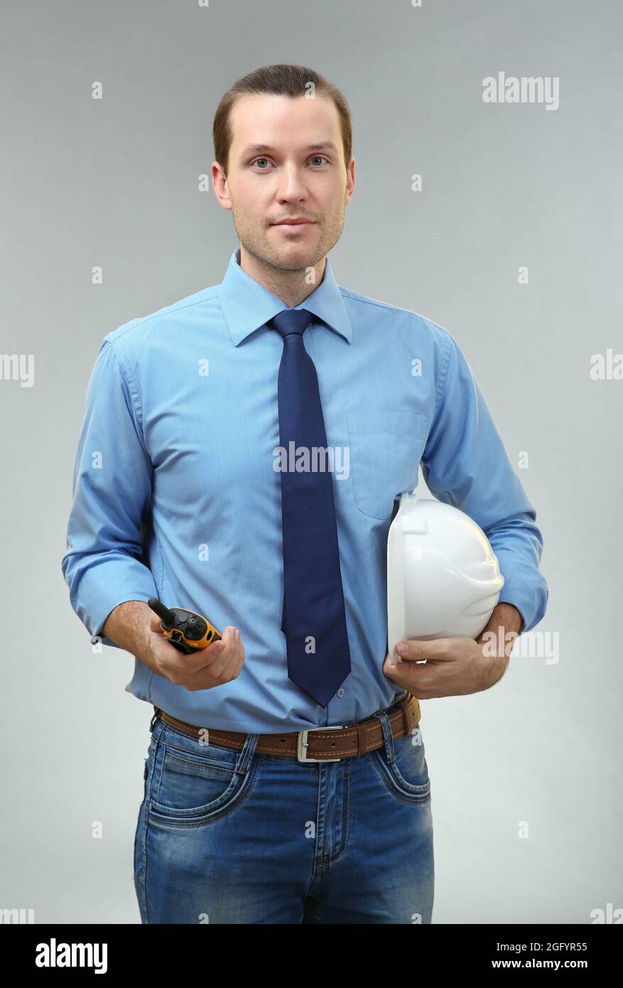 Handsome engineer with portable radio transmitter on light background ...
