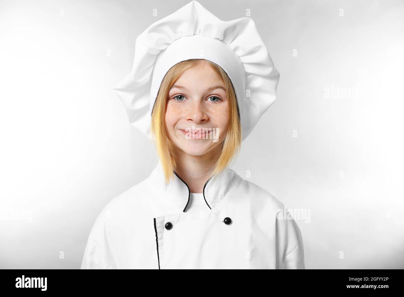 Cute girl in chef uniform on light background Stock Photo - Alamy