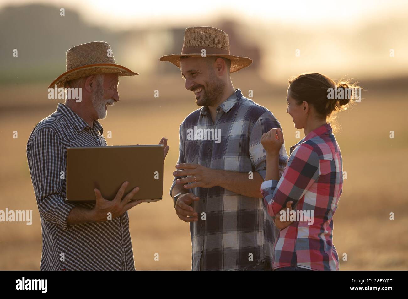 Senior experienced farmer with laptop explaining something to younger ...