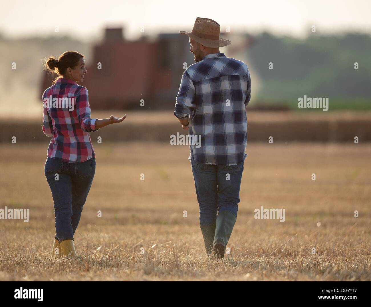 Rear view of two farmers man and woman walking and smiling on wheat ...
