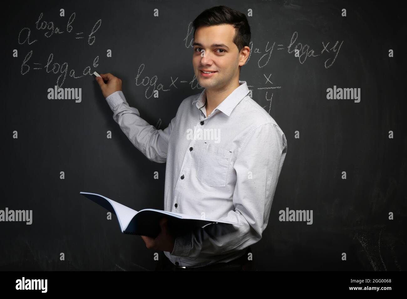 Handsome young teacher writing math formulas on blackboard Stock Photo ...