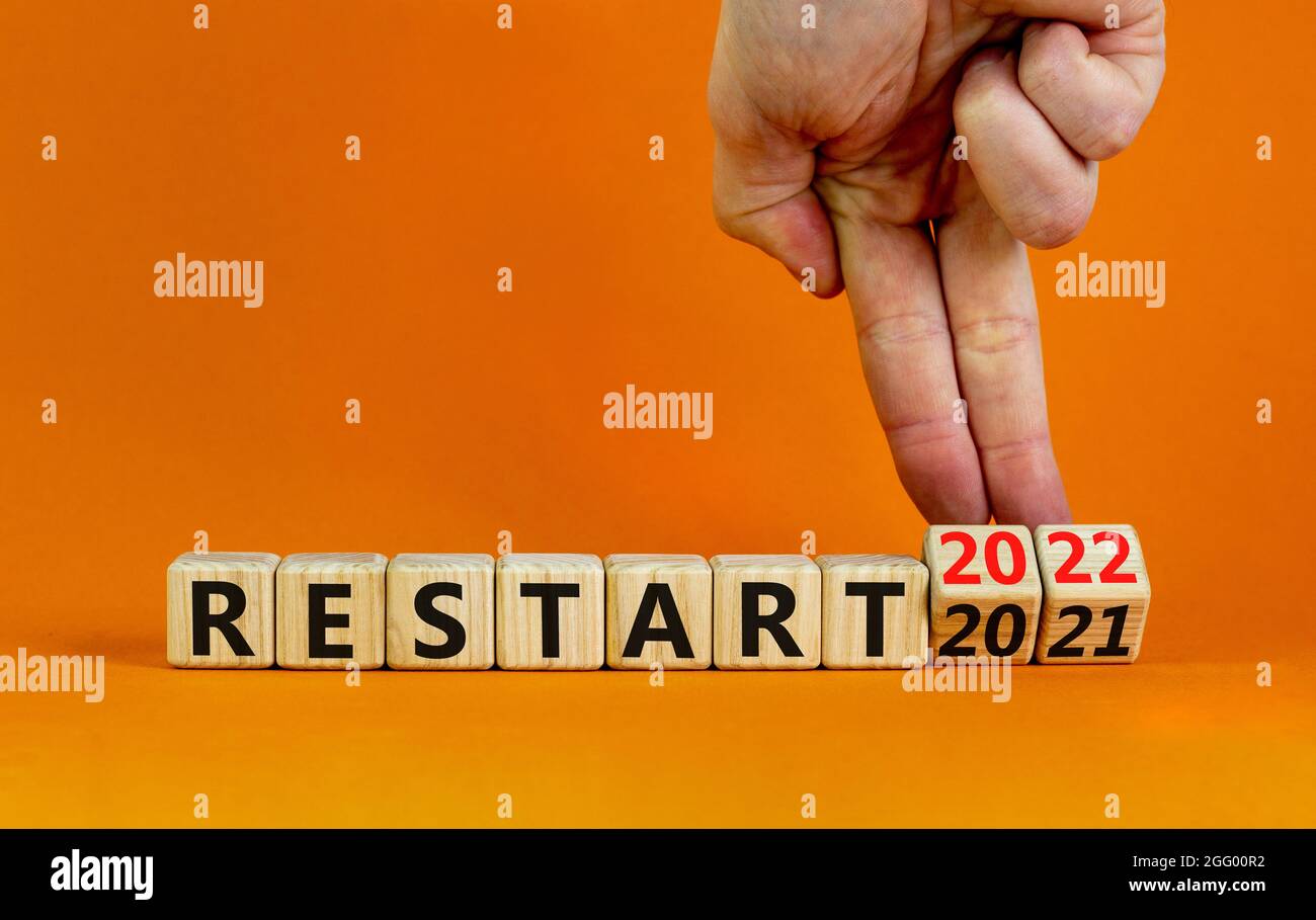 2022 restart new year symbol. Businessman turns a wooden cube and changes words 'Restart 2021 ...