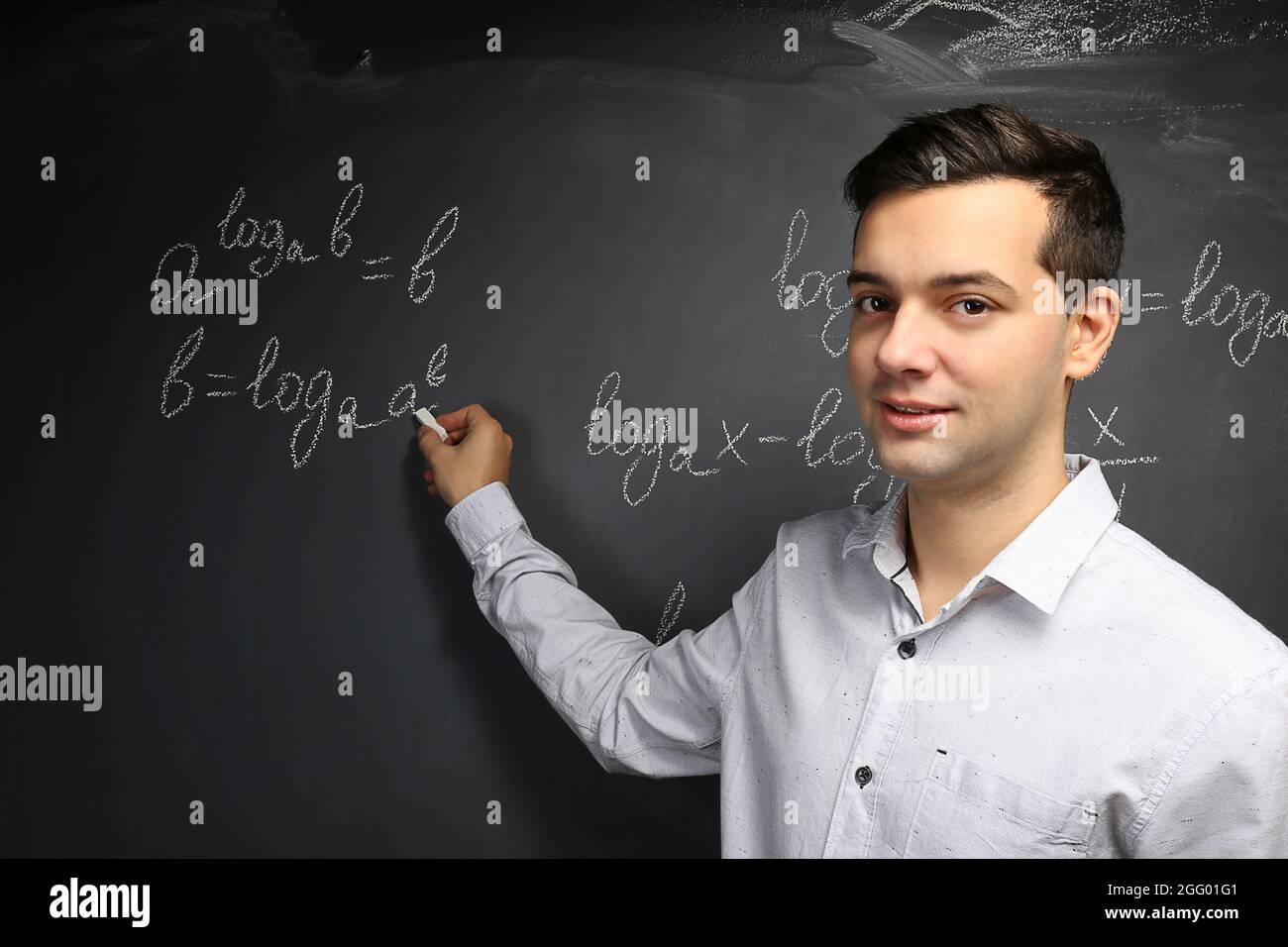Handsome young teacher writing math formulas on blackboard Stock Photo ...