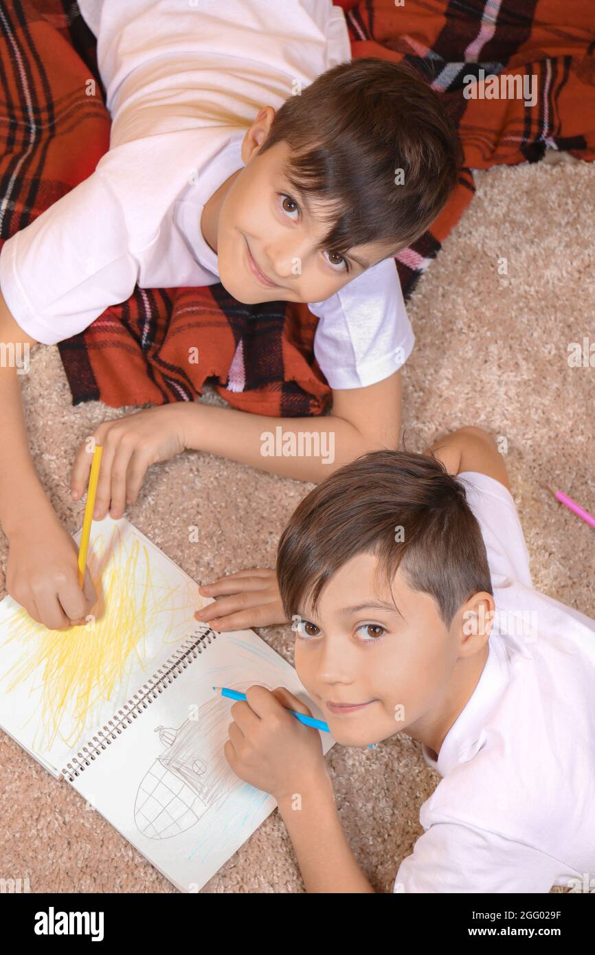 Twin brothers drawing in notebook on floor Stock Photo - Alamy