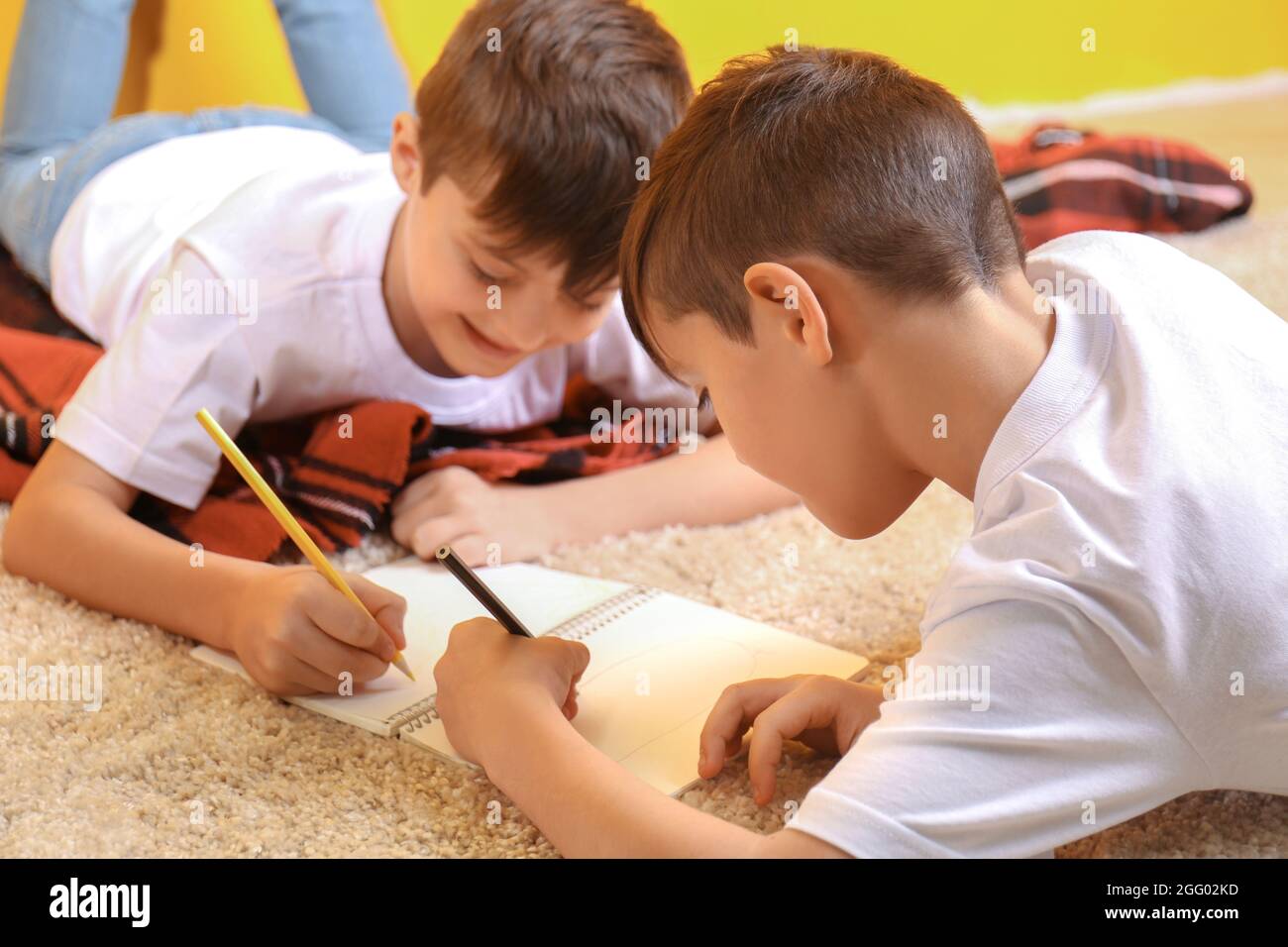 Twin brothers drawing in notebook on floor Stock Photo - Alamy