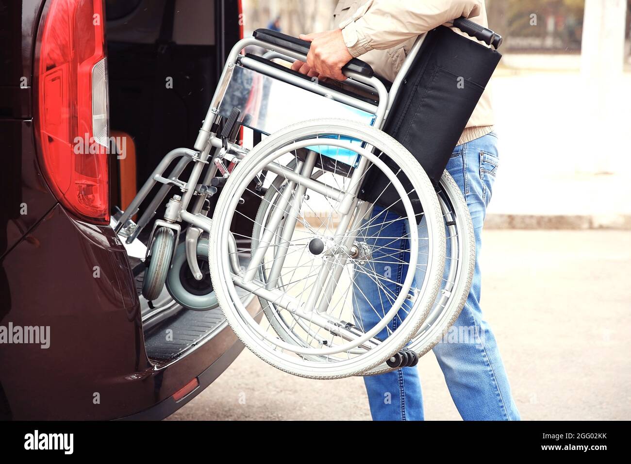 Man loading wheelchair of handicapped person Stock Photo - Alamy