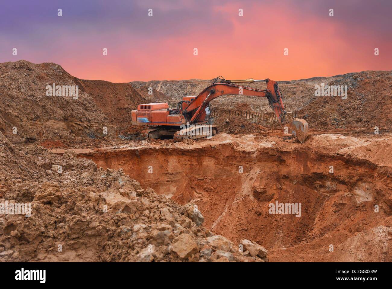 Excavator during earthmoving work at open-pit mining on sunset ...