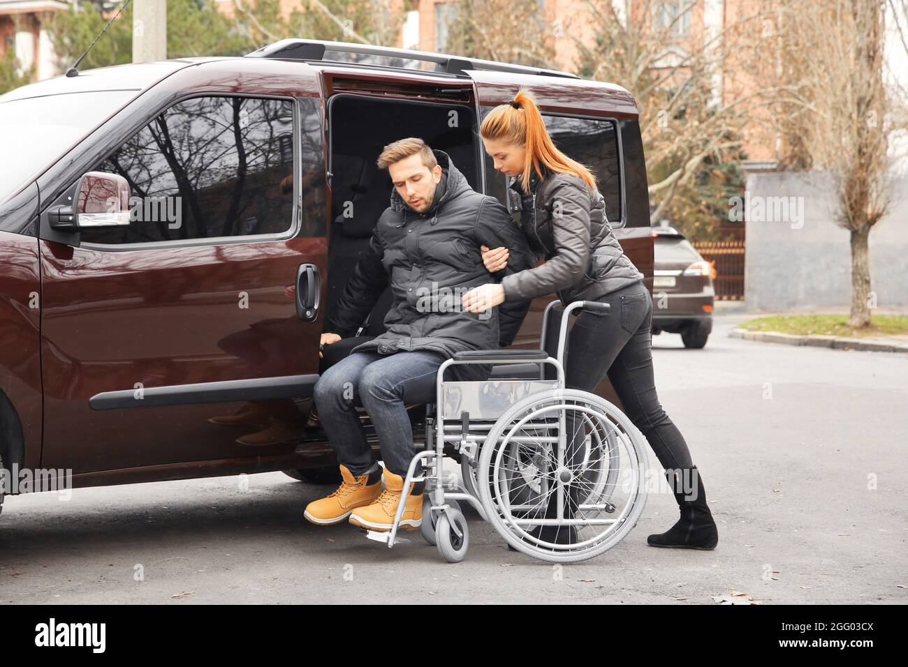 Young woman helping handicapped man to sit in wheelchair Stock Photo ...