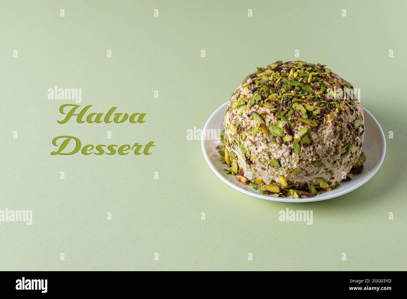 Halva with chopped pistachios on white plate on green paper background ...
