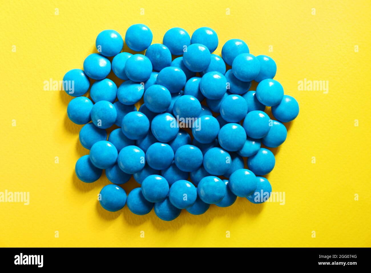 Blue candies on yellow background Stock Photo - Alamy