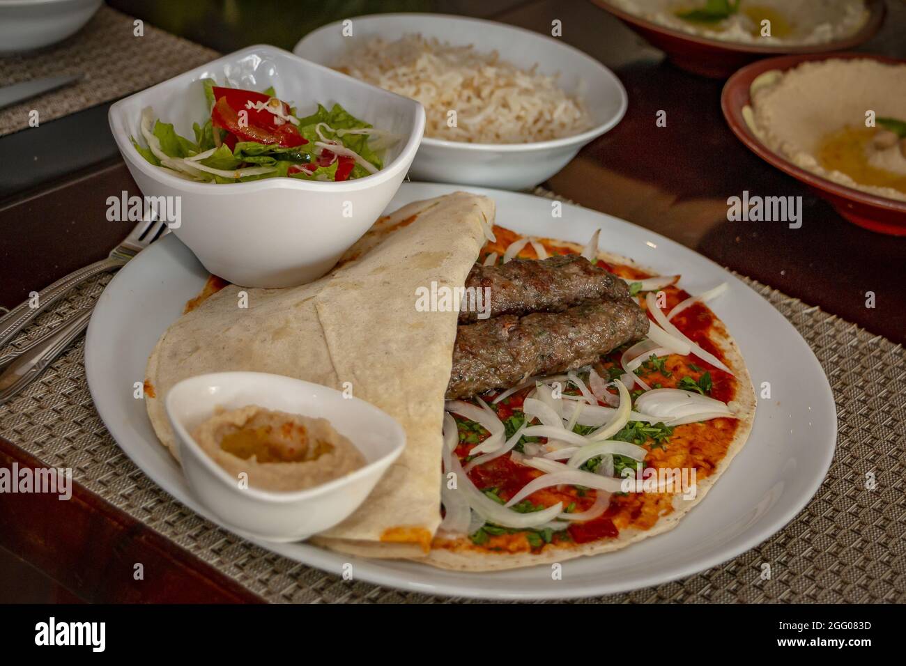 A Middle Eastern meal composed of pita, kebab, salad, hummus, rice and ...