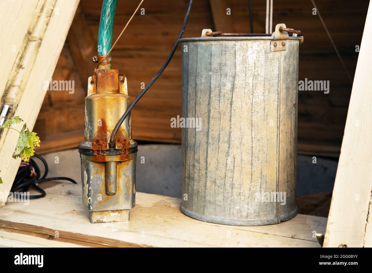Old rusty electric well pump and a metallic bucket stnding in the ...
