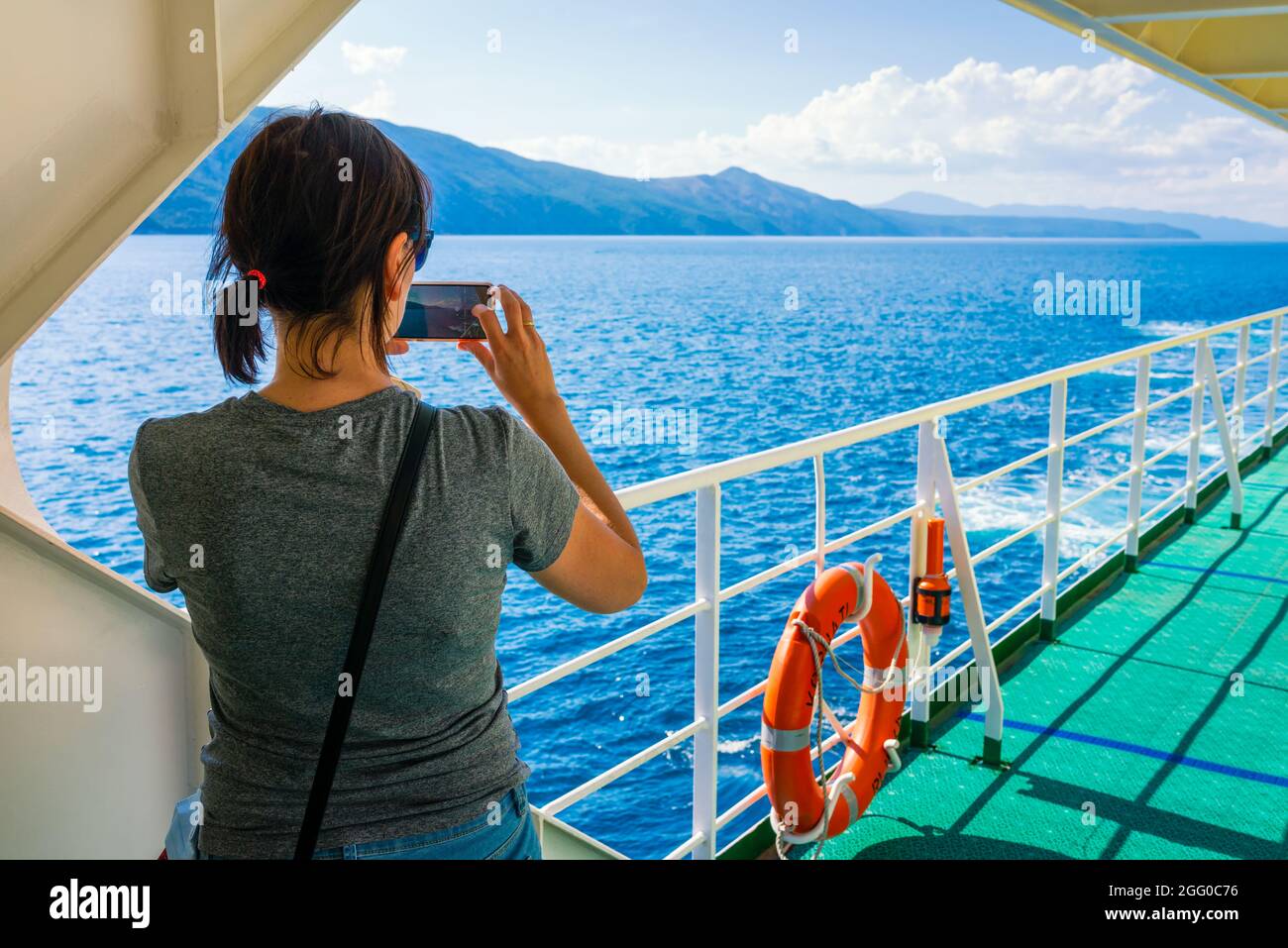 Woman tourist on the ferry on the way to vacation taking a photo with ...