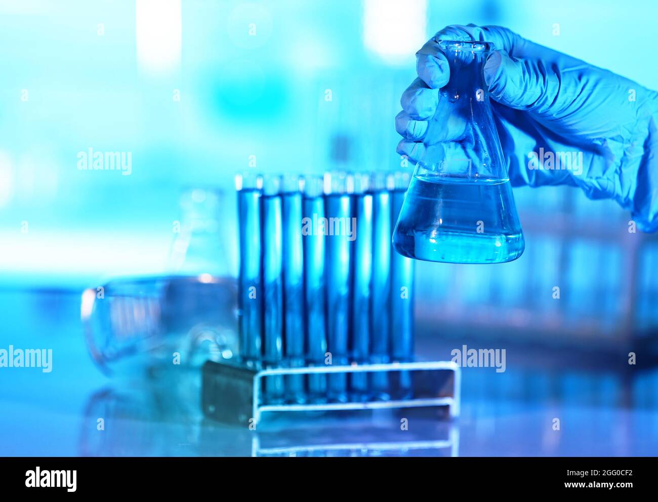 Hand in glove holding flask on blurred background Stock Photo - Alamy