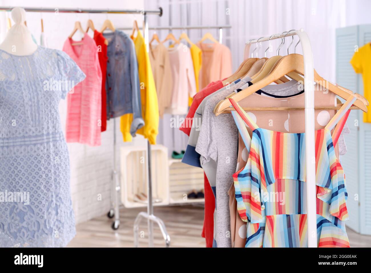 Fashionable clothes hanging on rack at room Stock Photo - Alamy