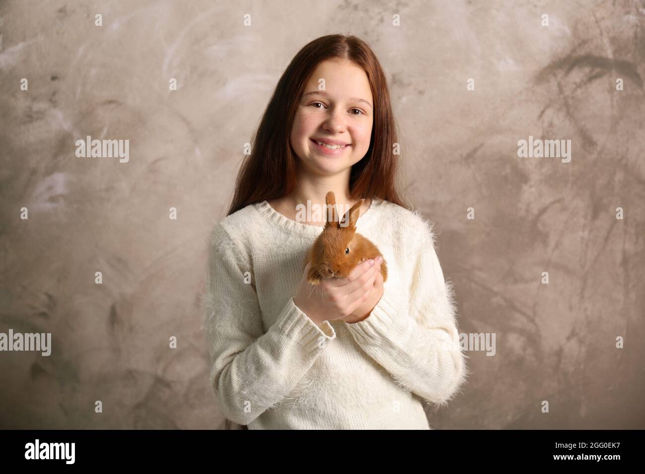 Cute girl holding rabbit on grey wall background Stock Photo - Alamy