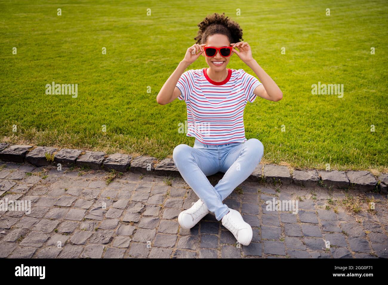 Full length body size young girl wearing sunglass sitting on the ground ...