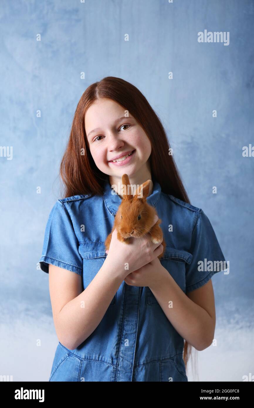 Cute girl holding rabbit on blue wall background Stock Photo - Alamy