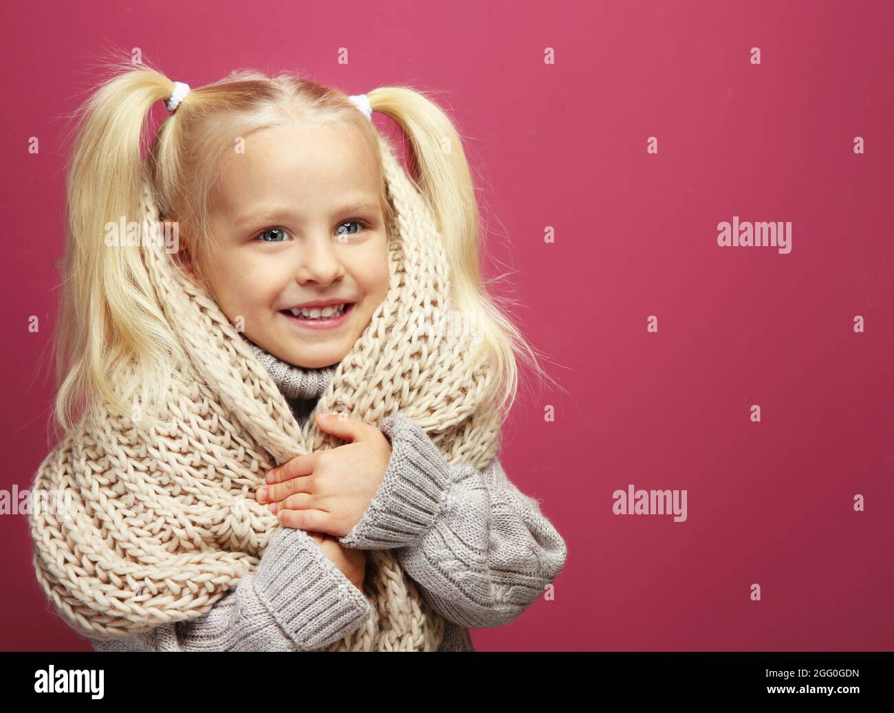 Funny little girl in warm clothes on color background Stock Photo - Alamy