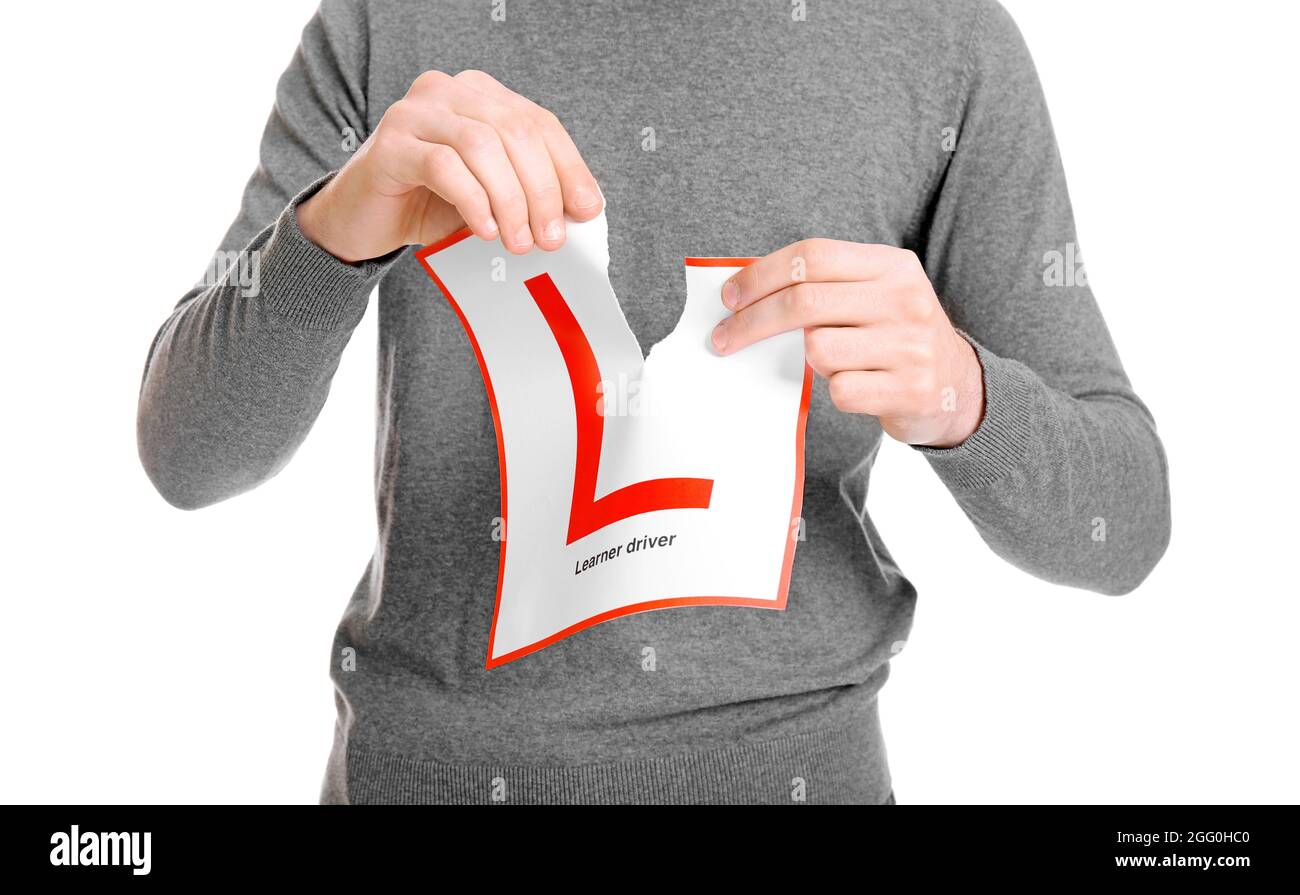 Young man tearing learner driver sign on white background, closeup ...