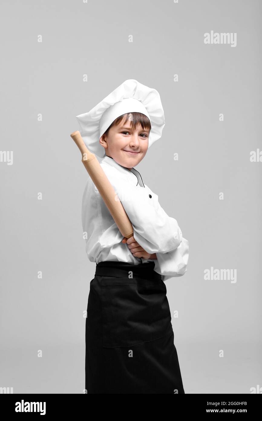 Cute boy in chef uniform on light background Stock Photo - Alamy