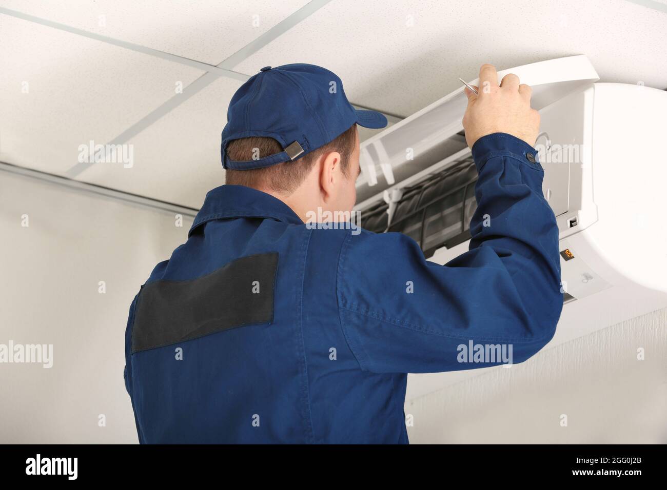 Worker carrying out maintenance of air conditioner in office Stock ...
