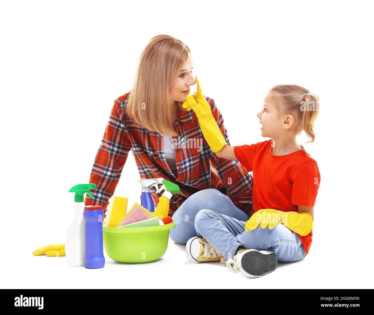 Little girl and her mother with cleaning supplies on white background ...