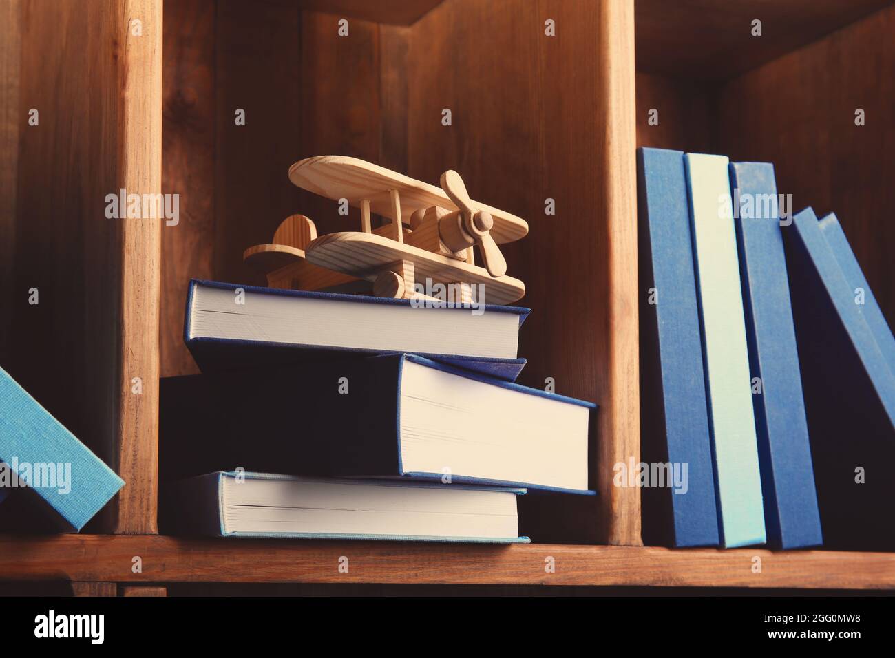Stack of books with airplane on wooden shelf Stock Photo - Alamy