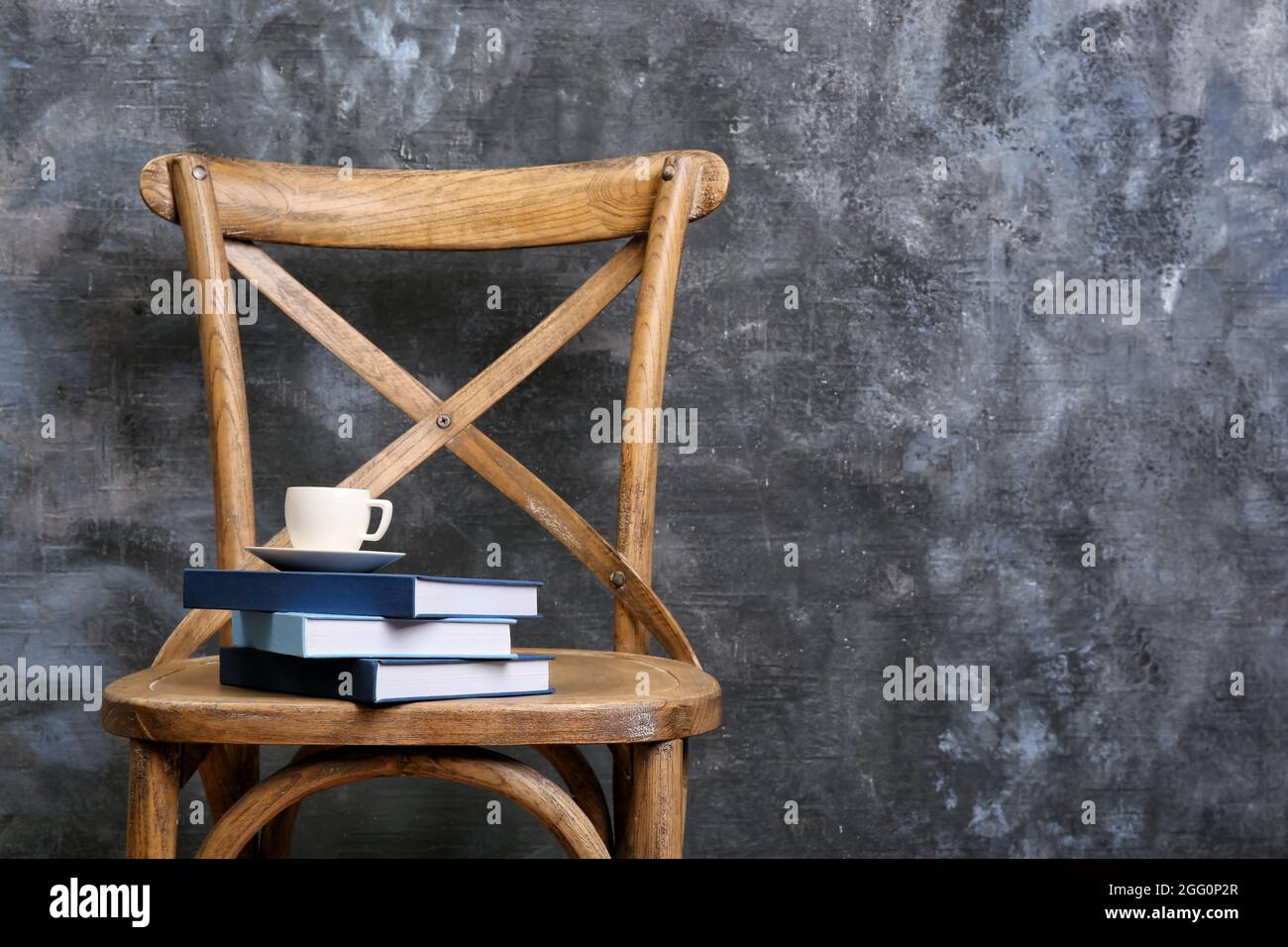 Stack of books on chair against gray wall background Stock Photo - Alamy