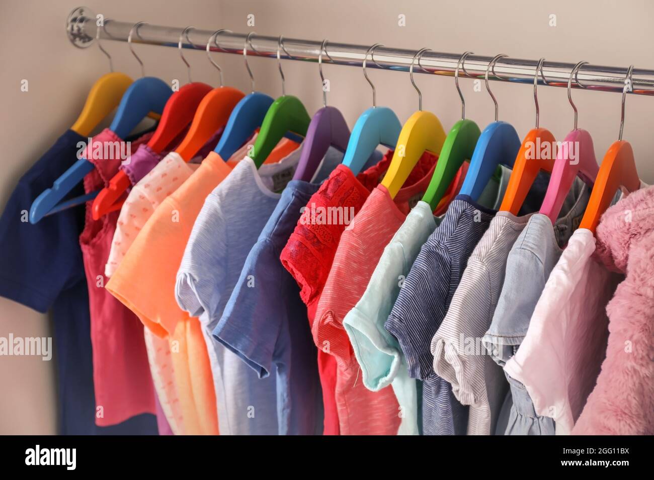 Colourful clothes on hangers in wardrobe Stock Photo - Alamy