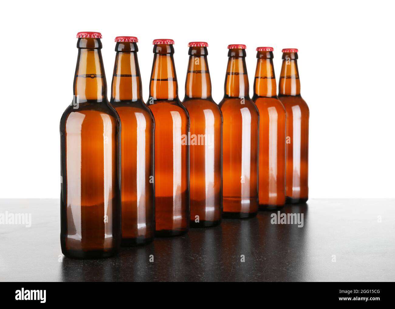 Bottles of beer on table against white background Stock Photo - Alamy