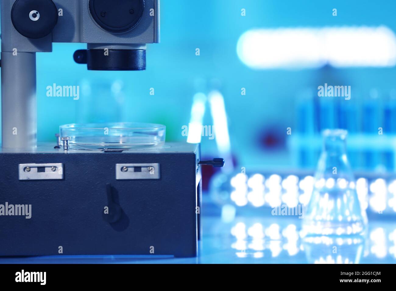 Microscope with chemical glassware on blurred background Stock Photo ...