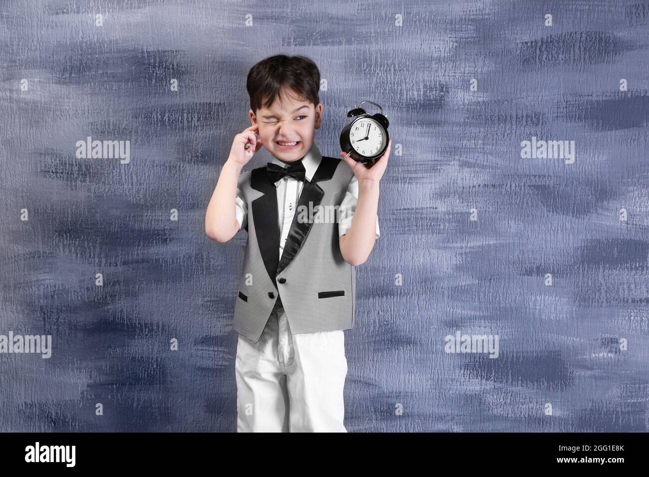 Cute little boy with alarm clock near color wall Stock Photo - Alamy