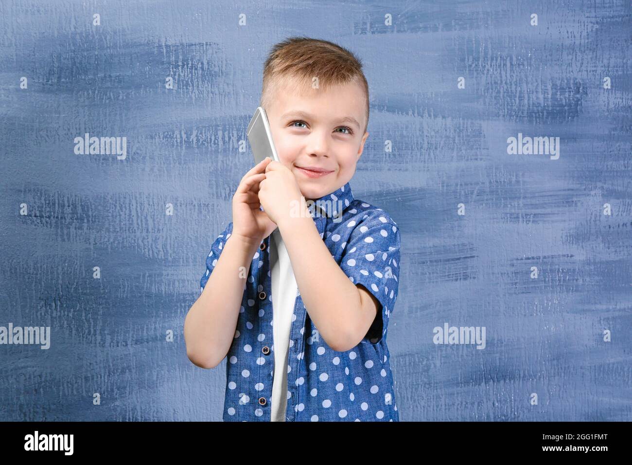 Cute little boy talking by mobile phone on color background Stock Photo ...