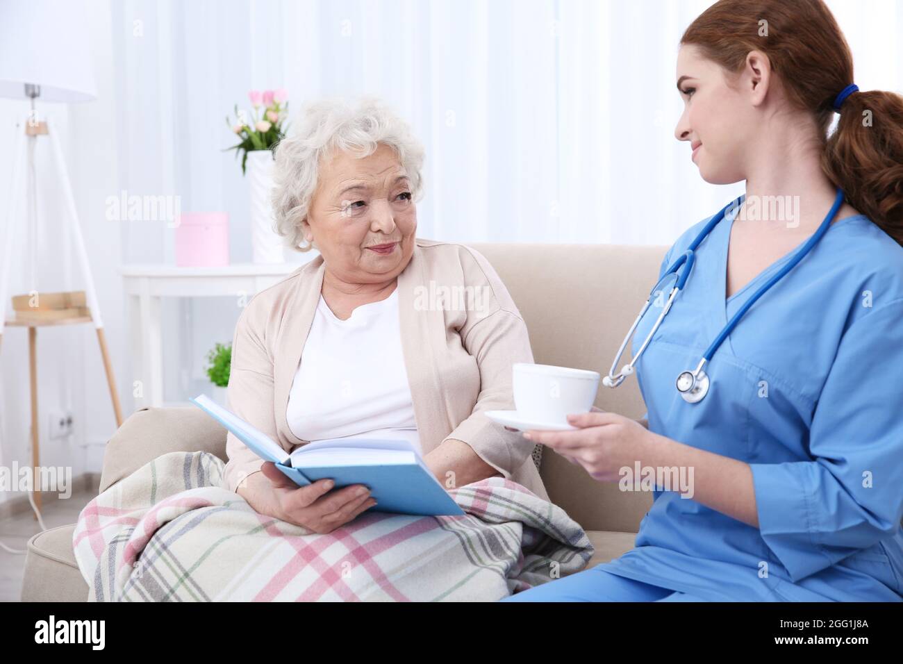 Nurse giving cup of tea to elderly women in light room Stock Photo - Alamy