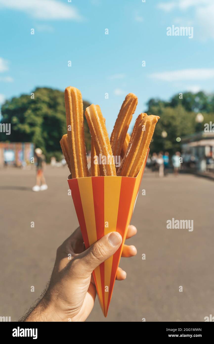 Churros waffles in hand on the street. Churros street food dessert made ...