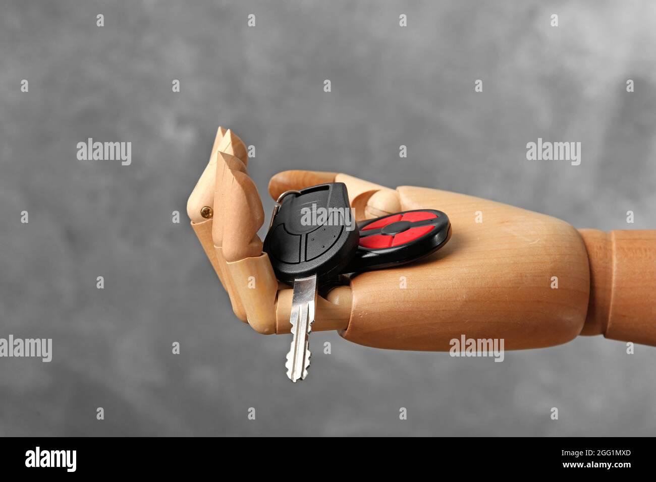 Wooden hand holding car keys on grey background Stock Photo - Alamy